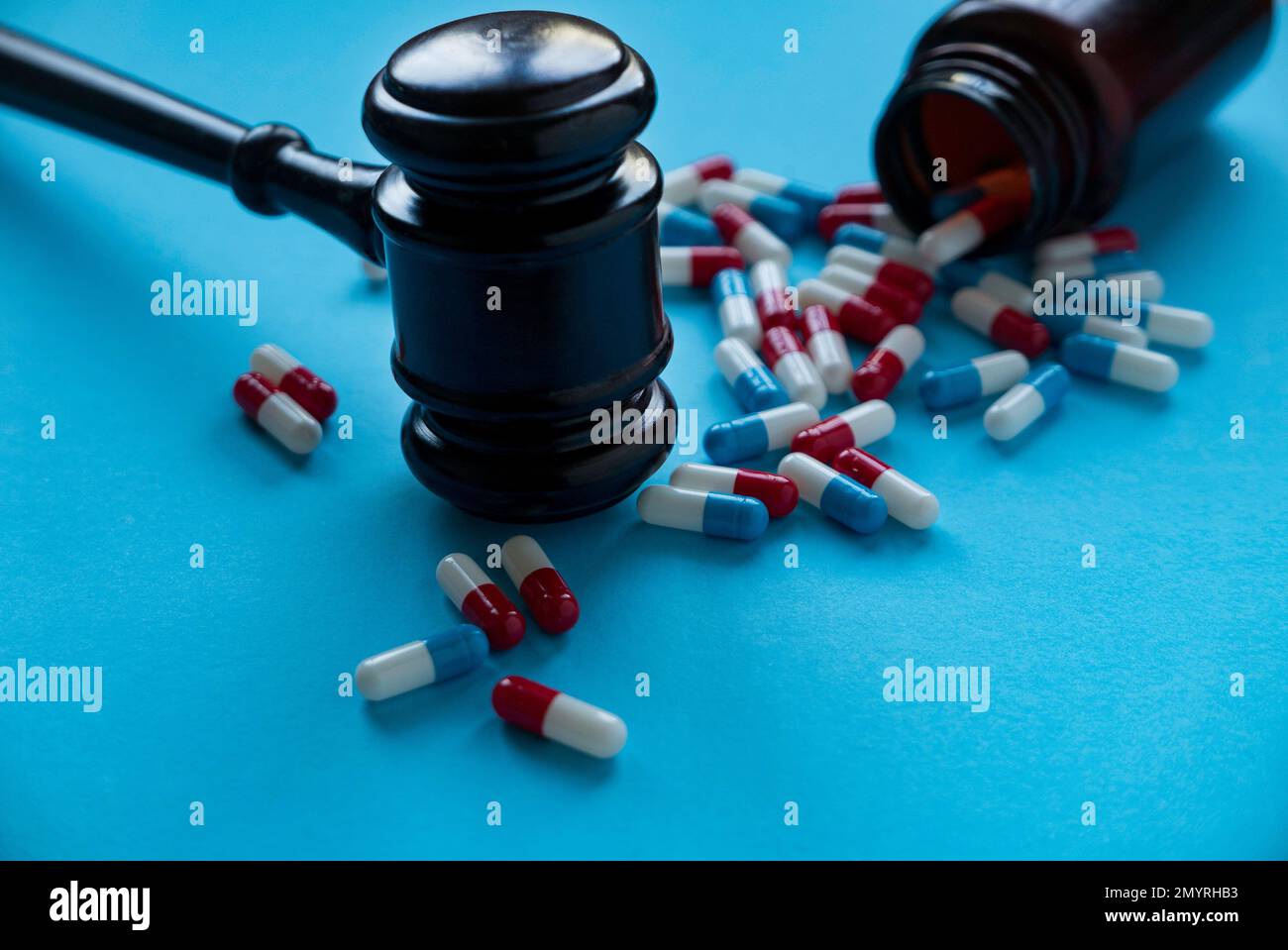 Medicine pills or capsules with a gavel on blue background. Drugs and ...