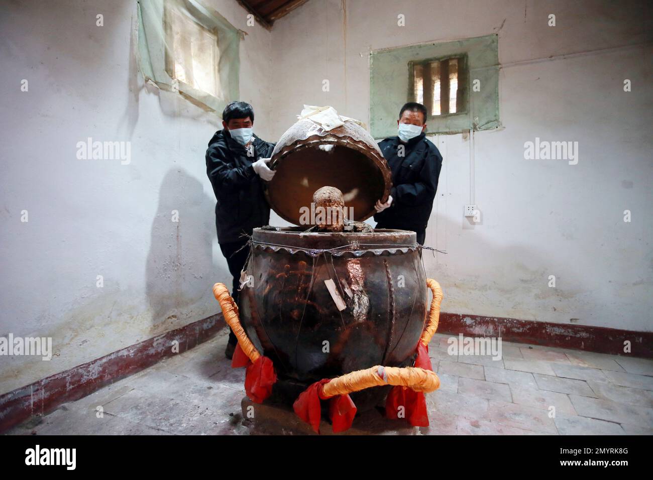 In this photo taken Sunday Jan. 10, 2016, men remove the top of a jar ...