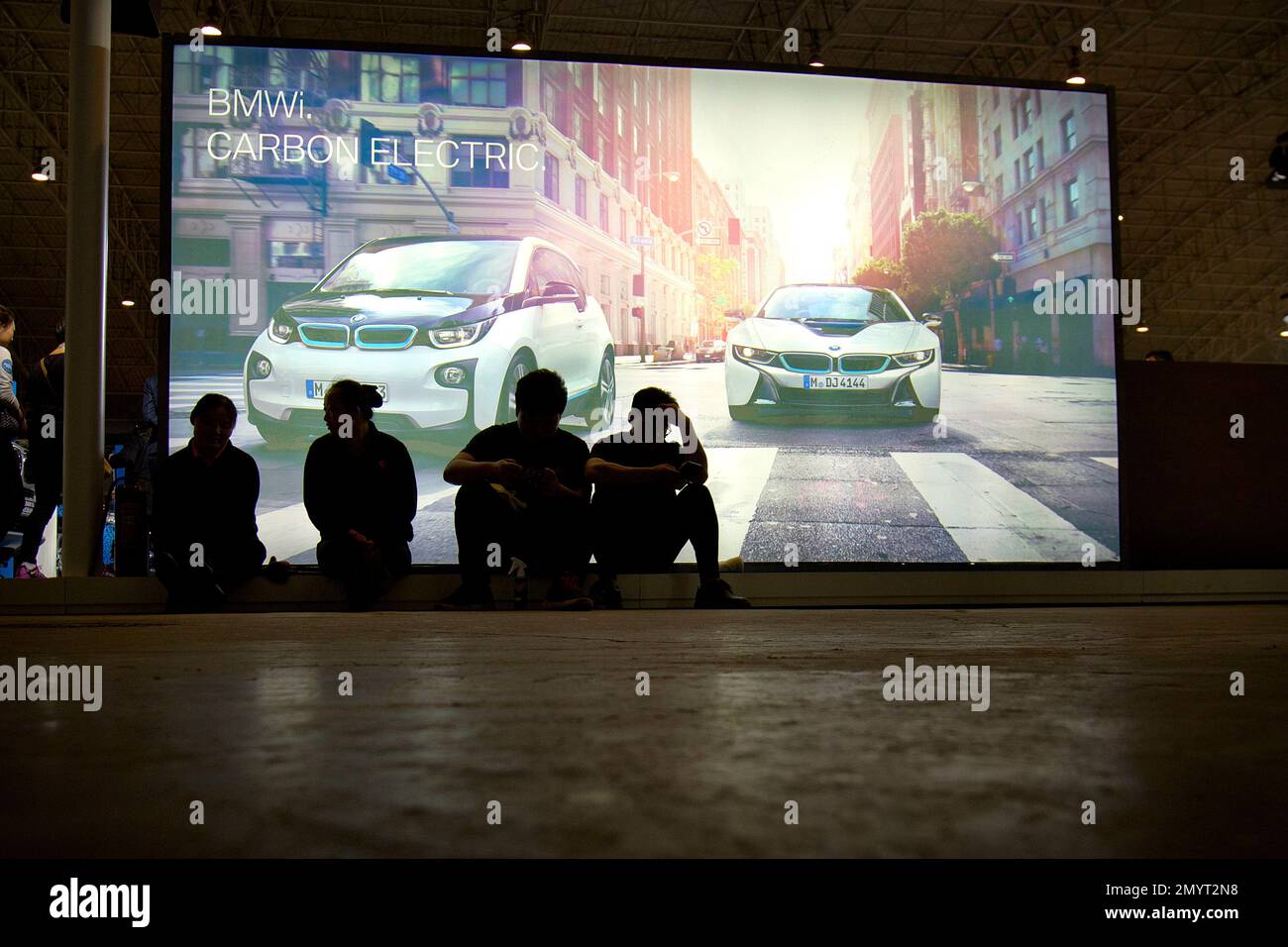 Workers take a break as they sit in front of a illuminated billboard ...