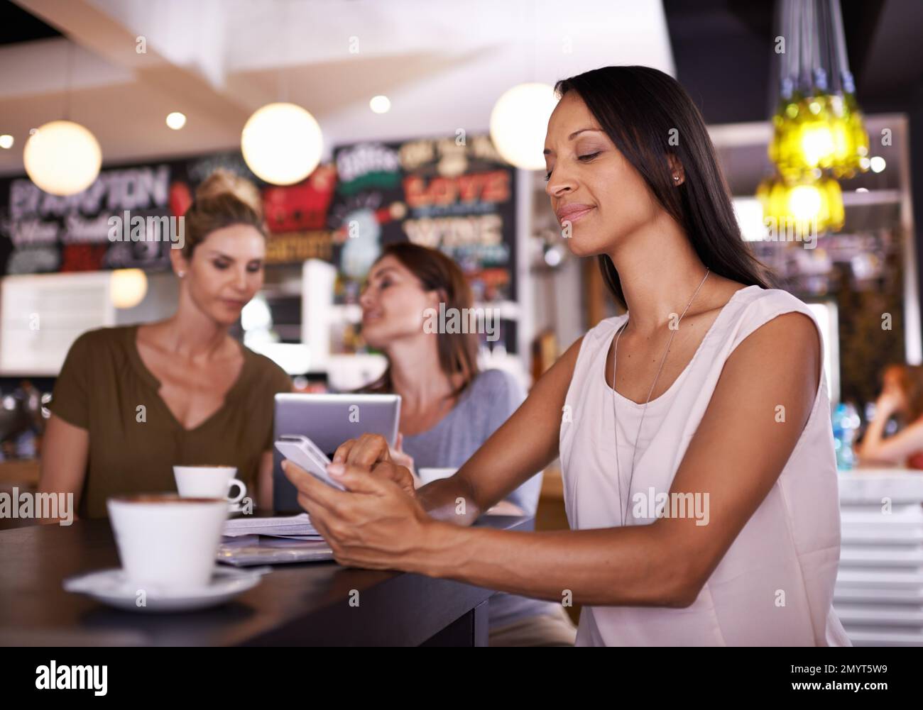 Getting things done outside the office. A woman texting in a restaurant ...