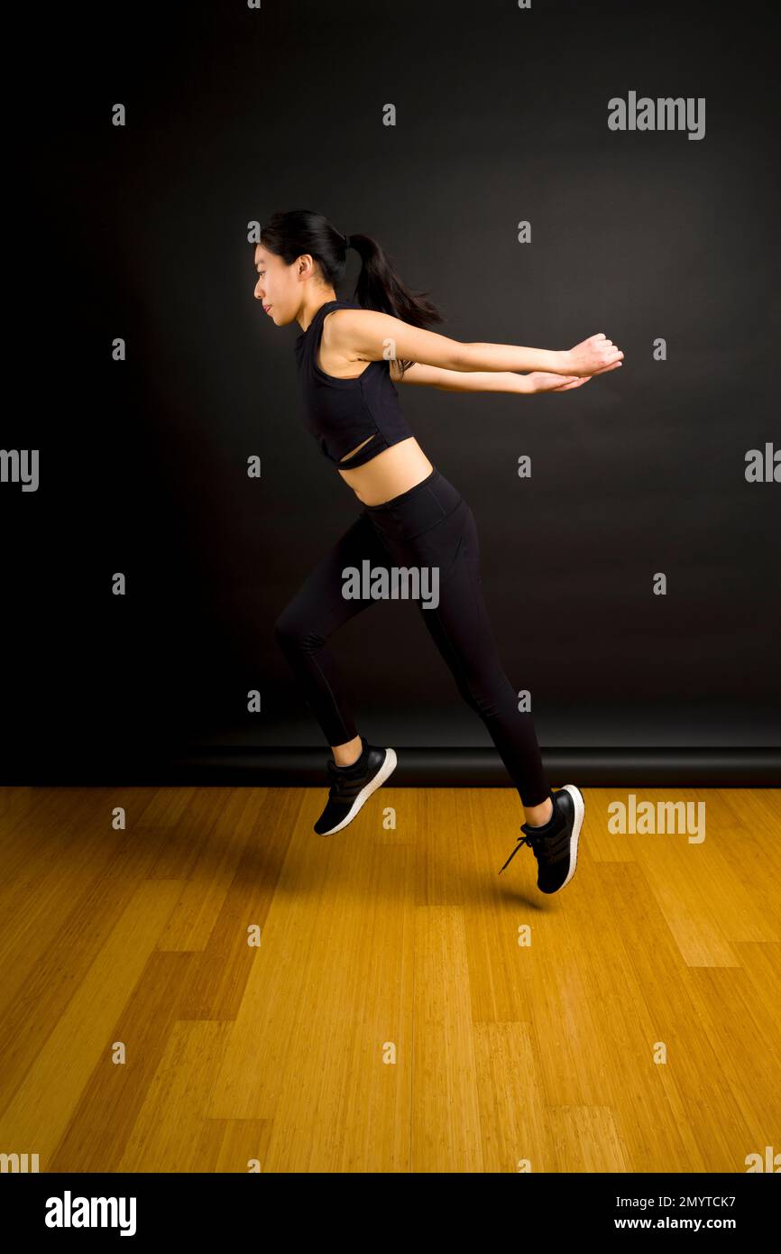 Side View of Young Asian Woman Lunging Forward Jumping | Black ...