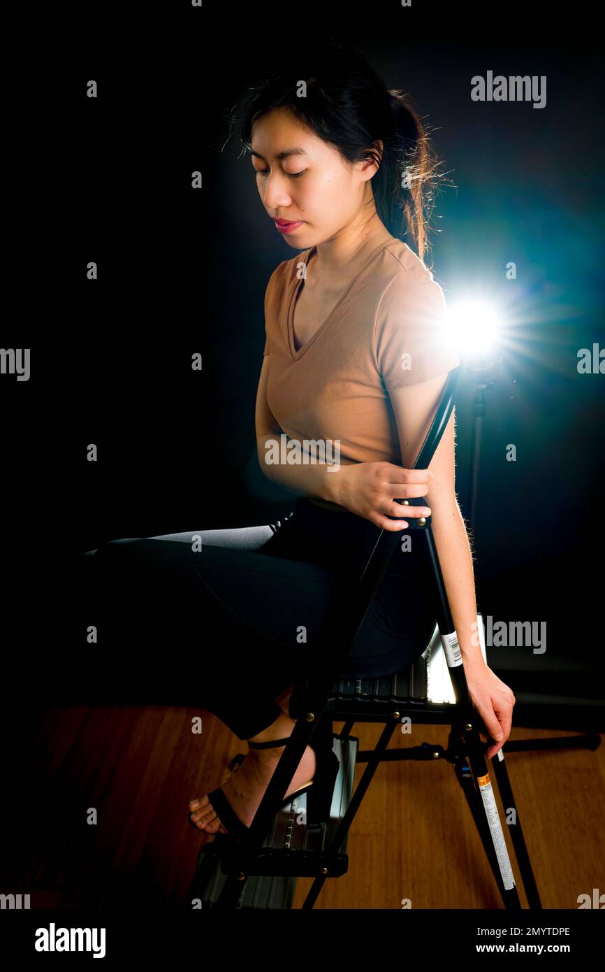 Side View of Young Asian Woman Sitting on a Ladder Looking Down | Flash ...