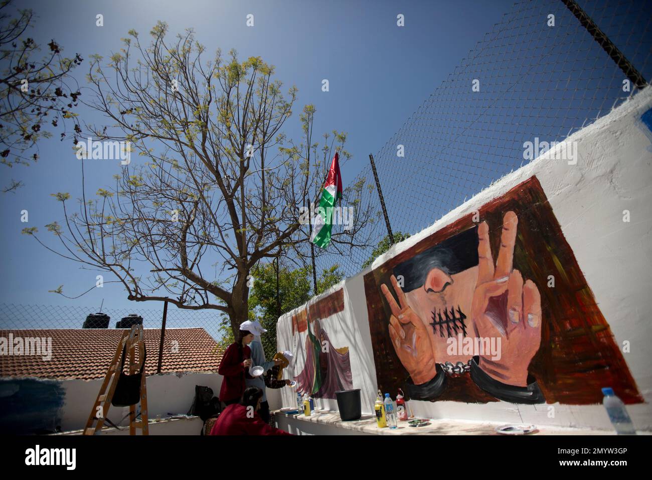 Palestinian students paint a mural marking Prisoners' Day, in the West ...