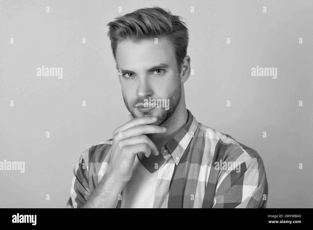 Handsome unshaven guy portrait stroking chin with serious look yellow ...