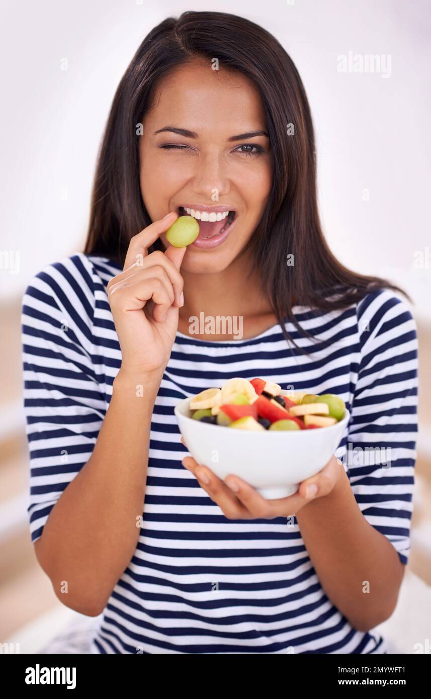 Taking a bursting bite. Portrait of a woman taking a bite of her grape ...