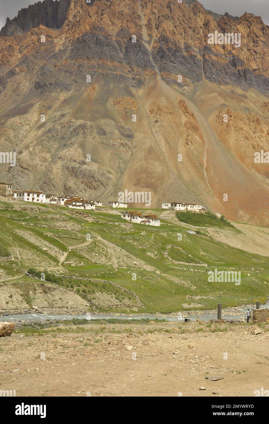 View of a village next to a beautiful rocky mountain with flowing a ...