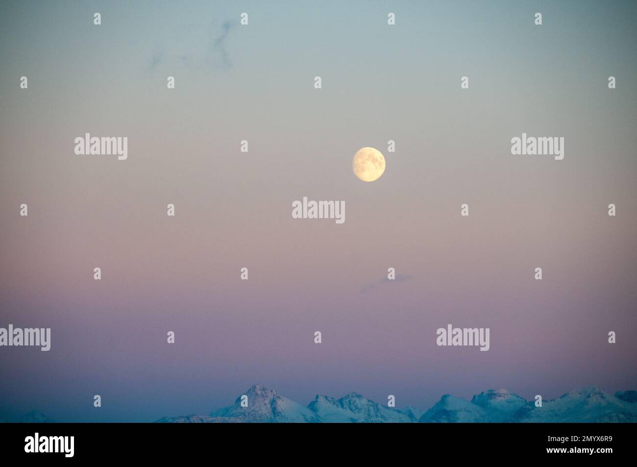 Landscape shot highlighting a near full moon over the rugged mountains ...