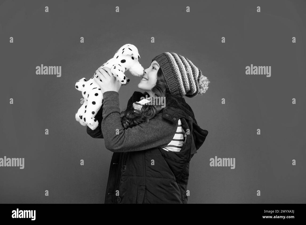 happy lovely child in puffer jacket hold toy. teen girl on red ...