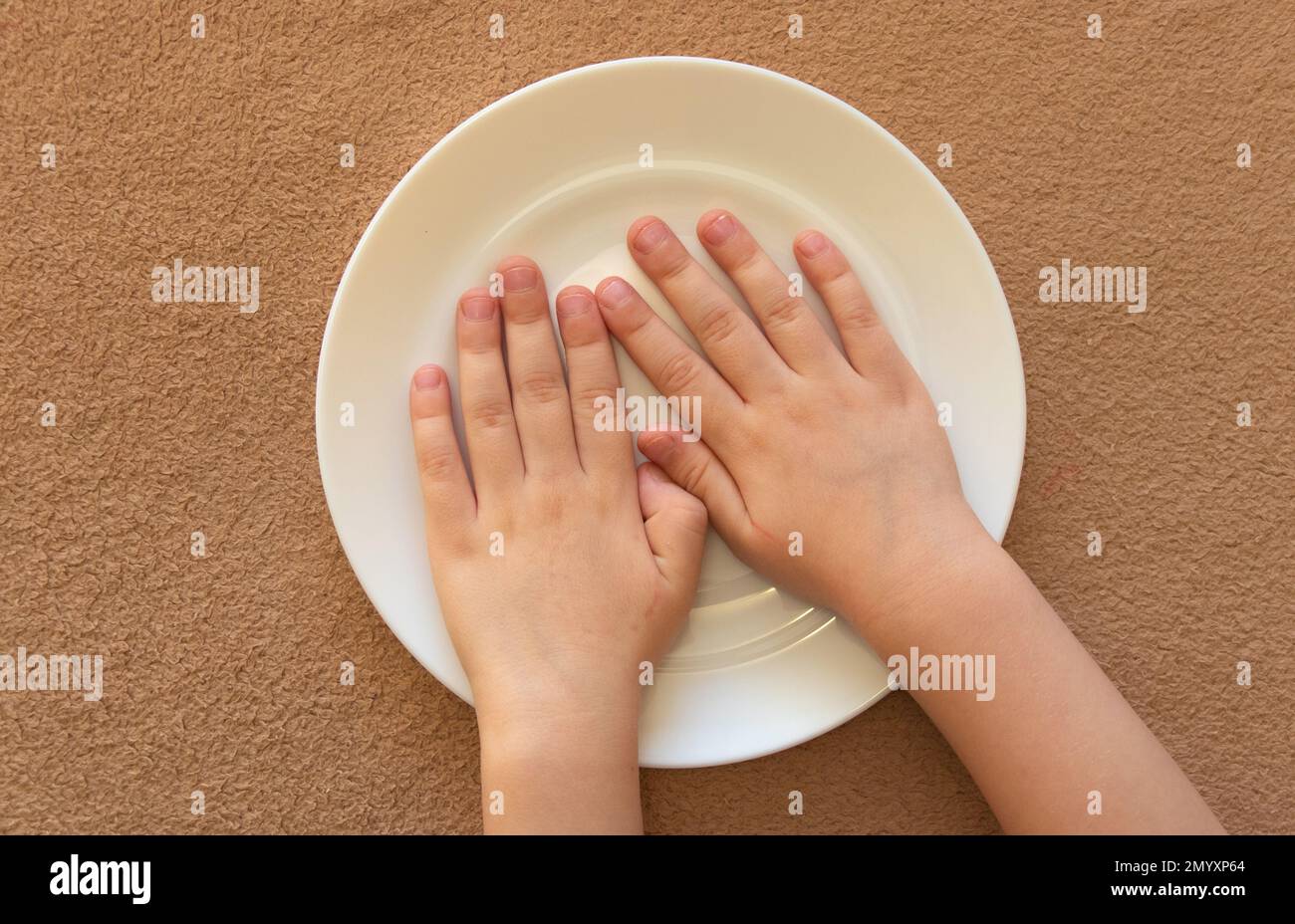 children's little hands lie in an empty plate on the table Stock Photo ...