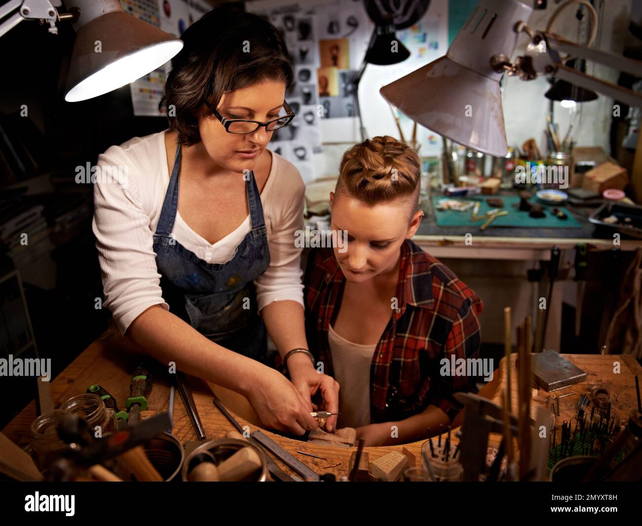 Showing her how its done. two young woman working on handmade crafts ...