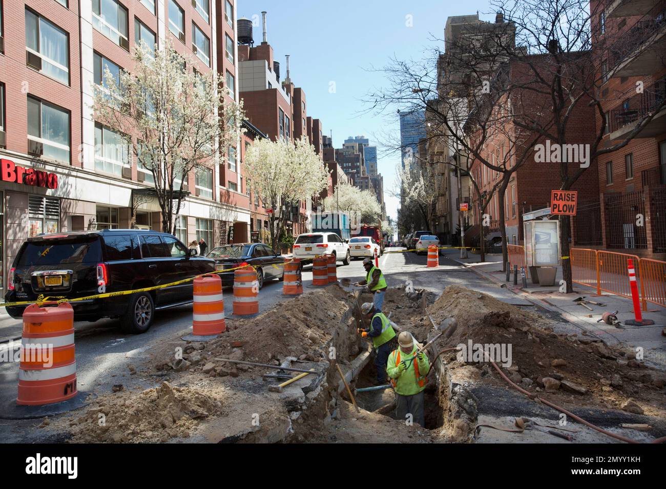 Utility workers dig in a street as they replace an aging water main ...