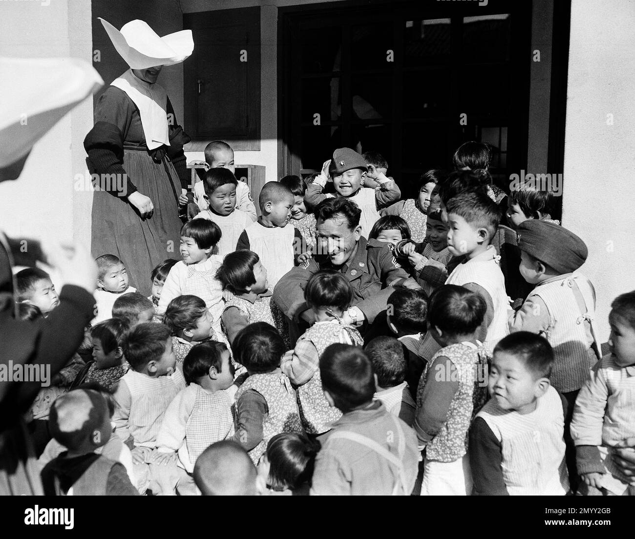 Smiling Japanese orphans vie for the attention of Sgt. Hugh O'Reilly, a ...