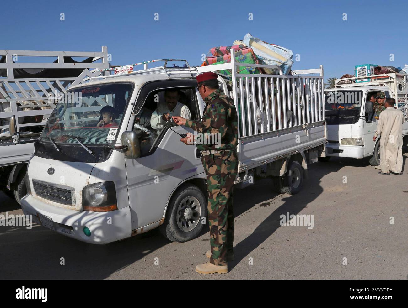 Iraqi security forces check identification documents at a checkpoint ...