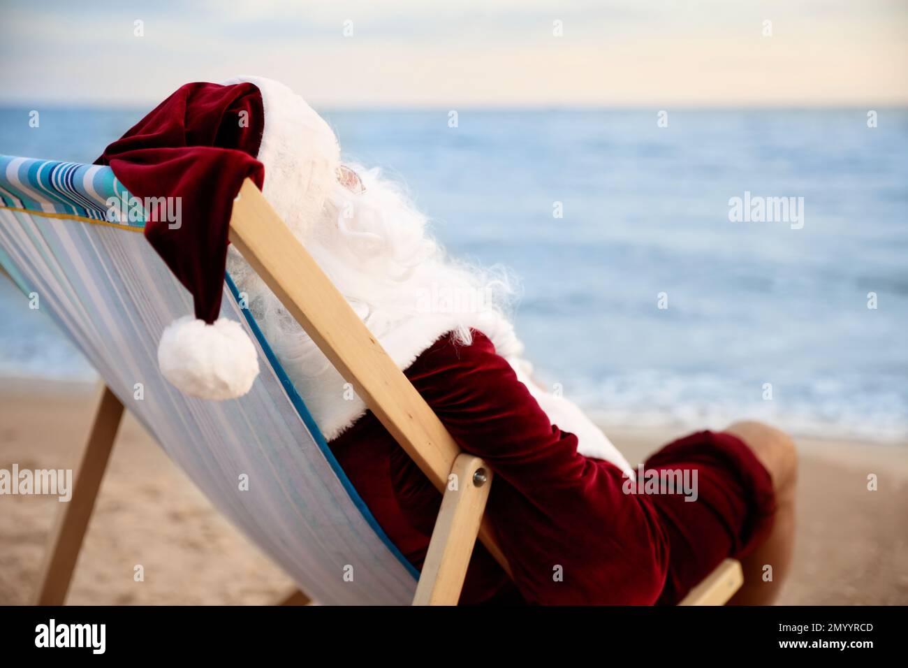 Santa Claus relaxing in chair on beach, space for text. Christmas ...