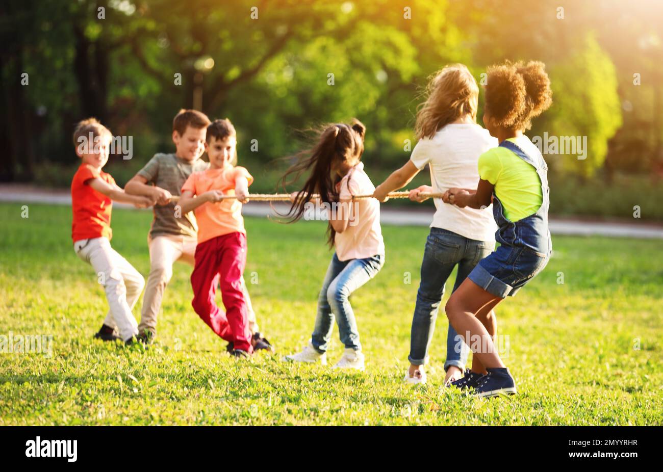School holidays. Group of happy children playing with rope outdoors ...