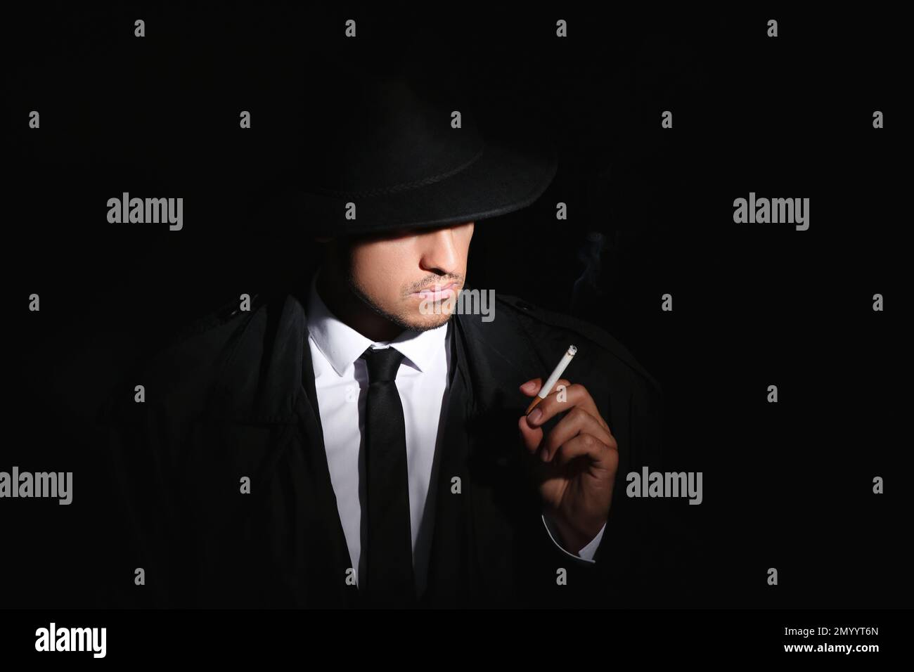 Old fashioned detective smoking cigarette on dark background Stock ...