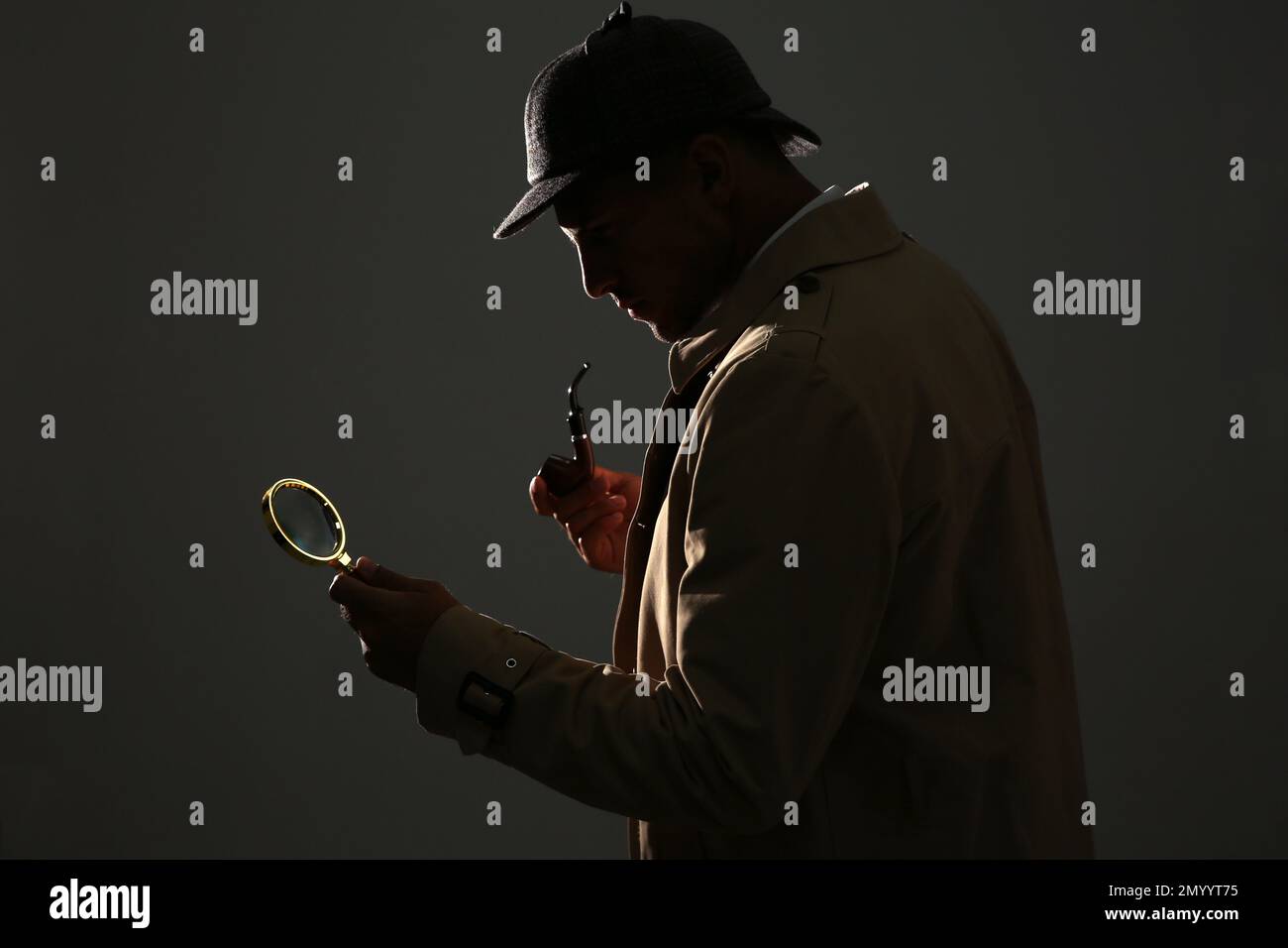 Old fashioned detective with smoking pipe and magnifying glass on dark ...