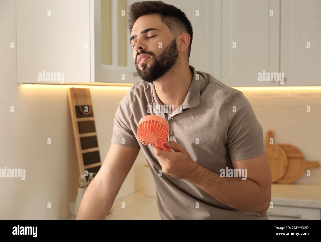 Man enjoying air flow from portable fan at home. Summer heat Stock ...