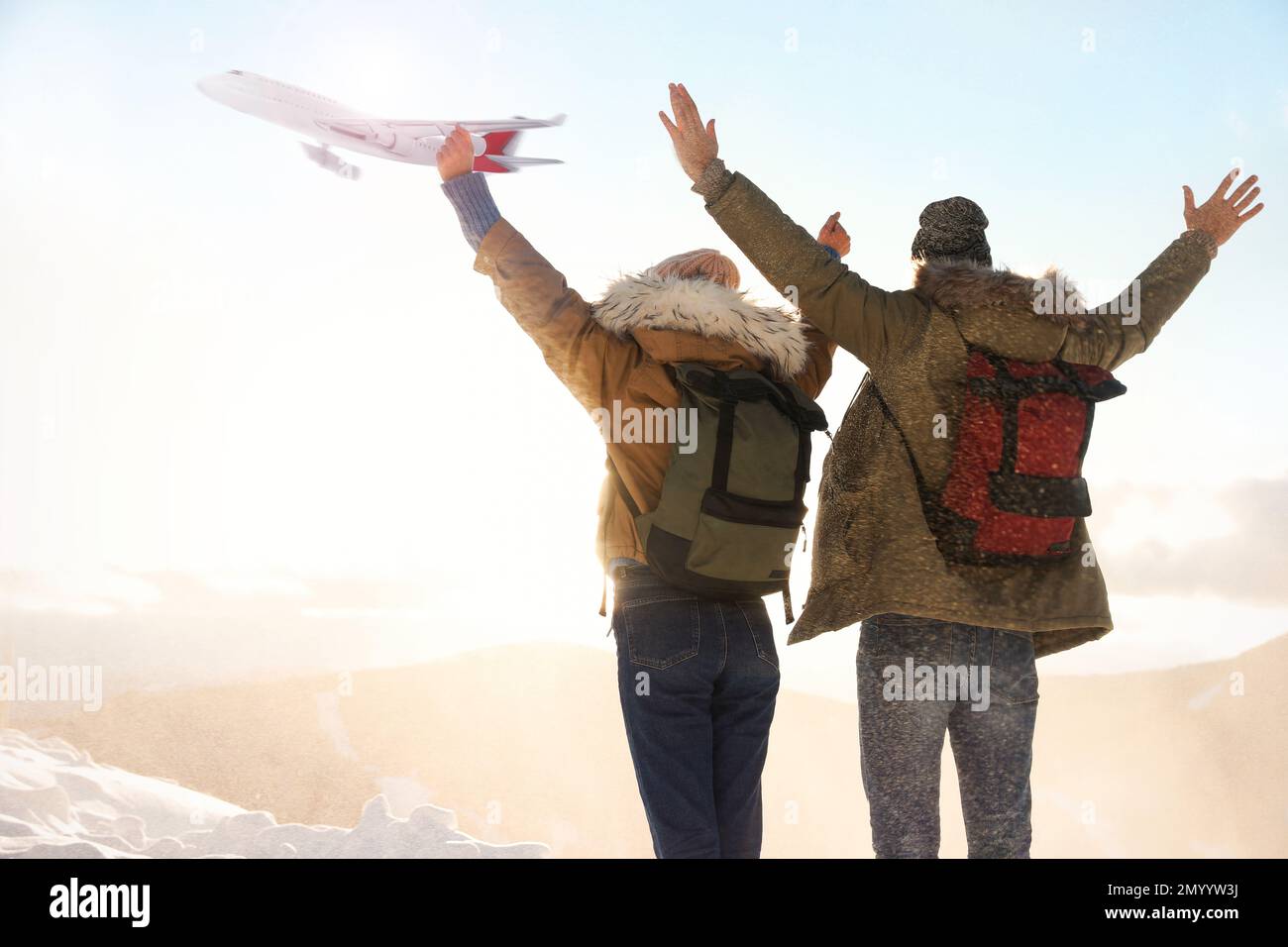 Excited couple in mountains under sky with flying airplane. Winter ...