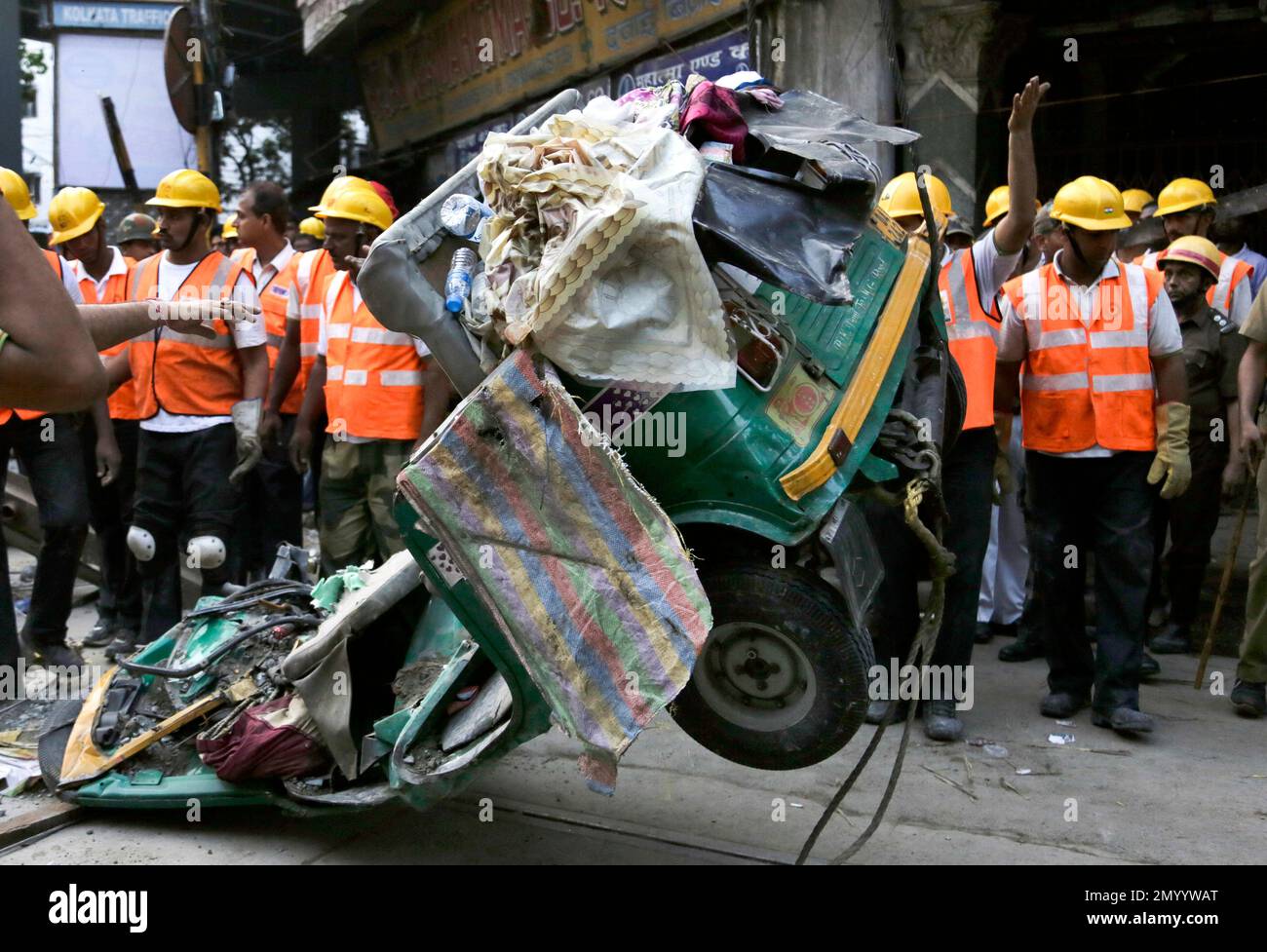 A damaged three-wheeled vehicle is taken out from the rubble of a ...