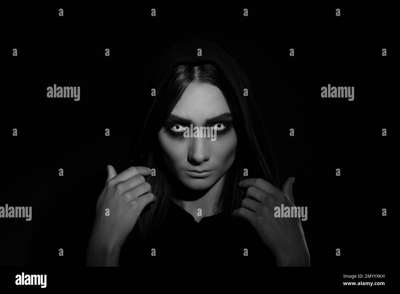 Mysterious witch with spooky eyes on dark background. Black and white ...
