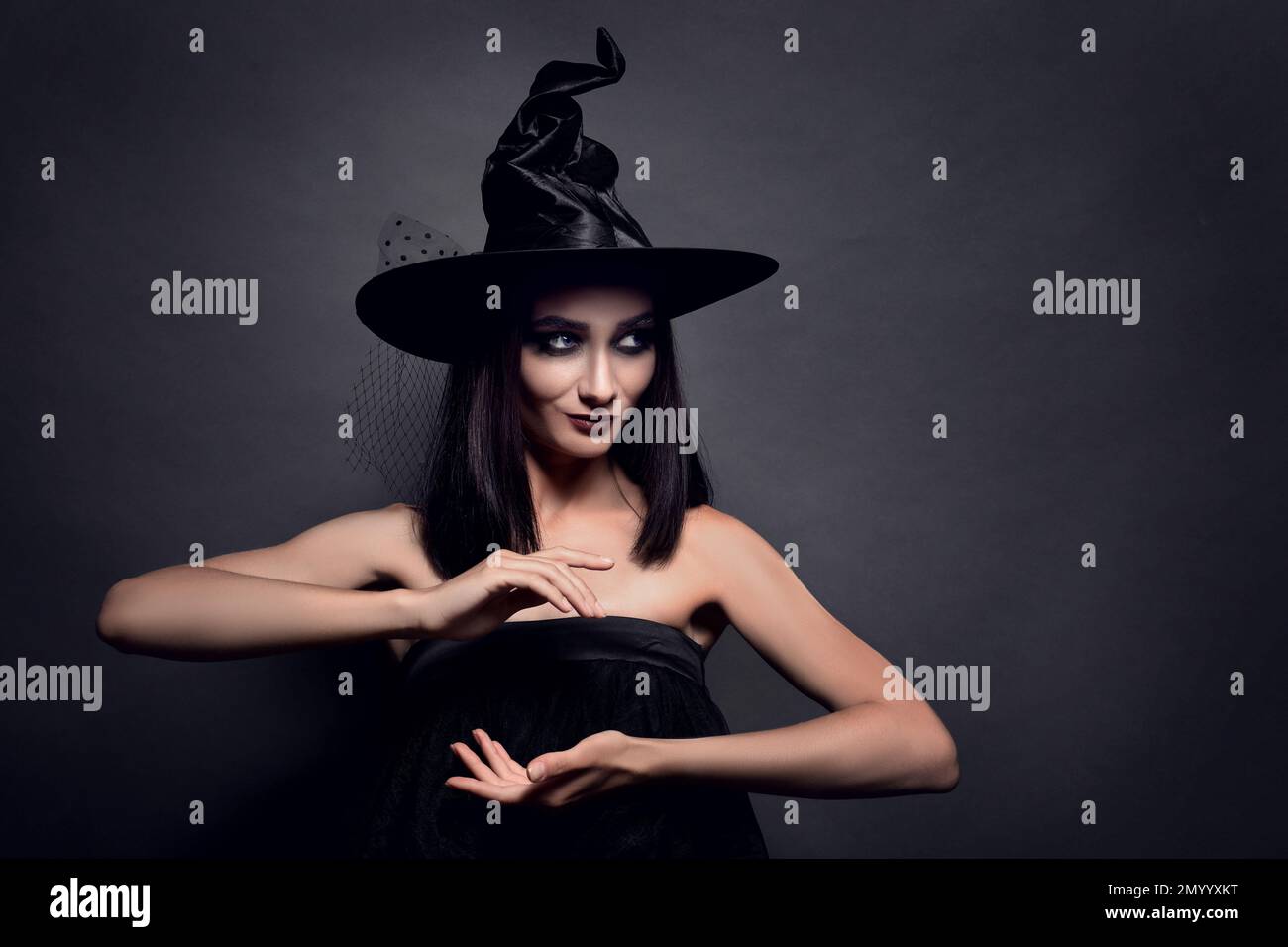 Mysterious witch wearing hat on black background Stock Photo - Alamy