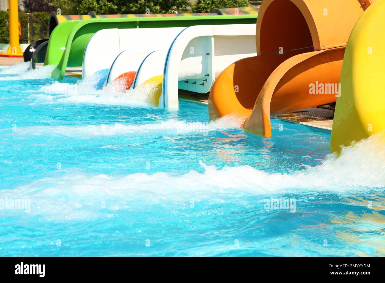 Different colorful slides and swimming pool in water park on sunny day ...