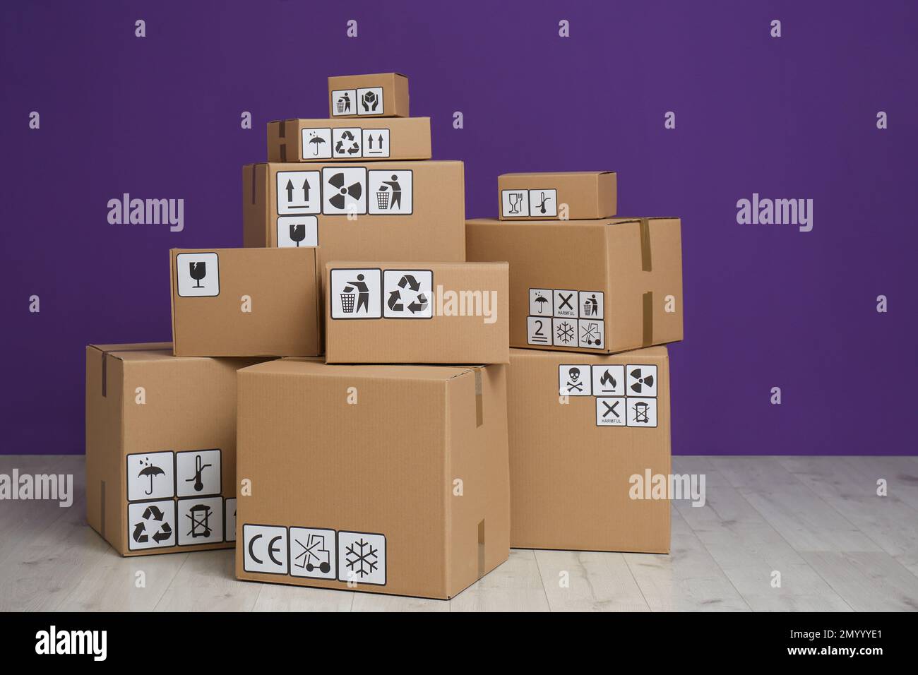Cardboard boxes with different packaging symbols on floor near purple ...
