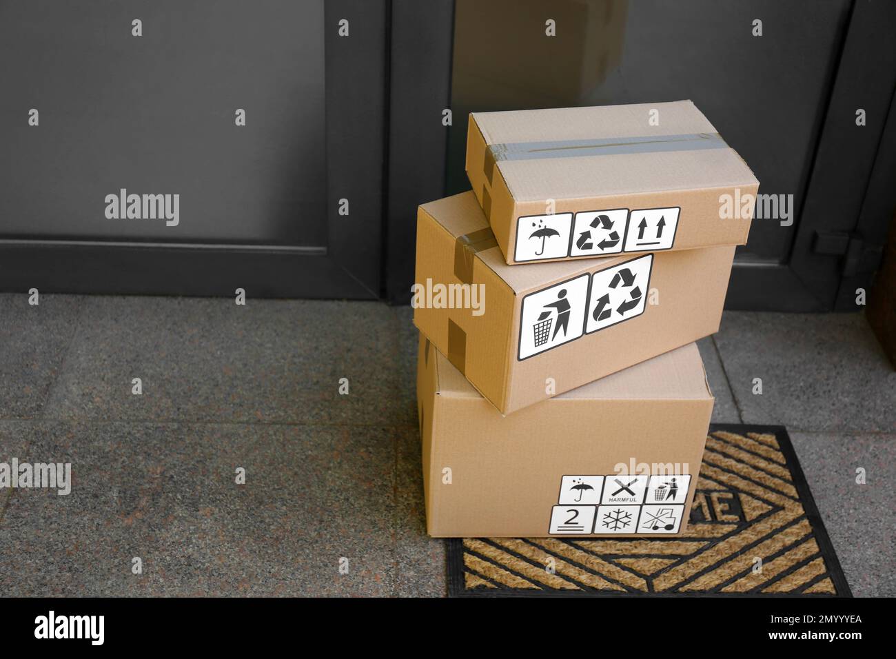 Cardboard boxes with different packaging symbols on door mat near ...