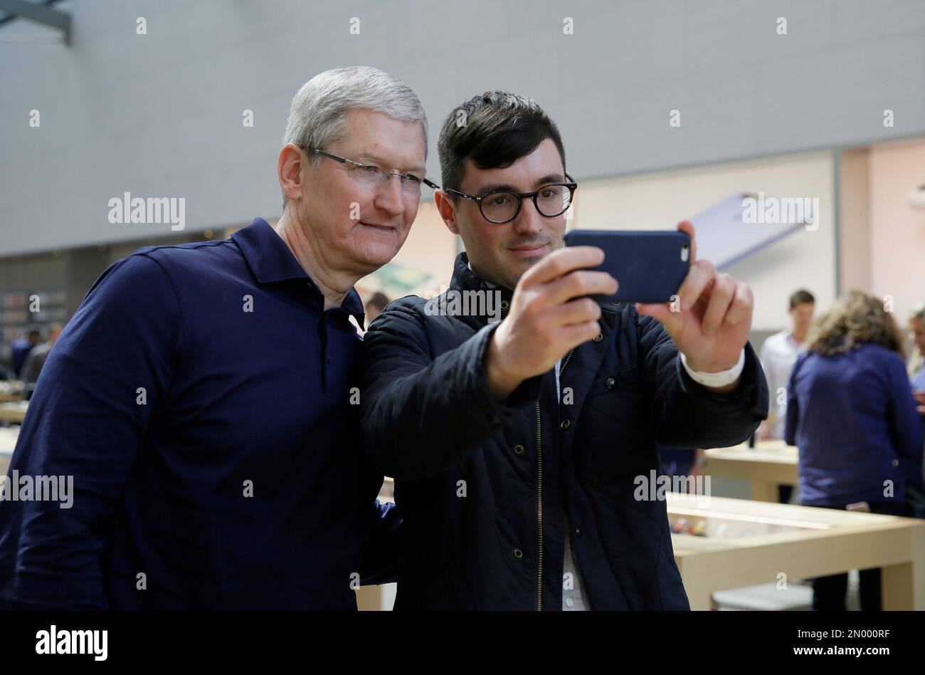 Apple CEO Tim Cook poses for a selfie with a customer during a visit to ...