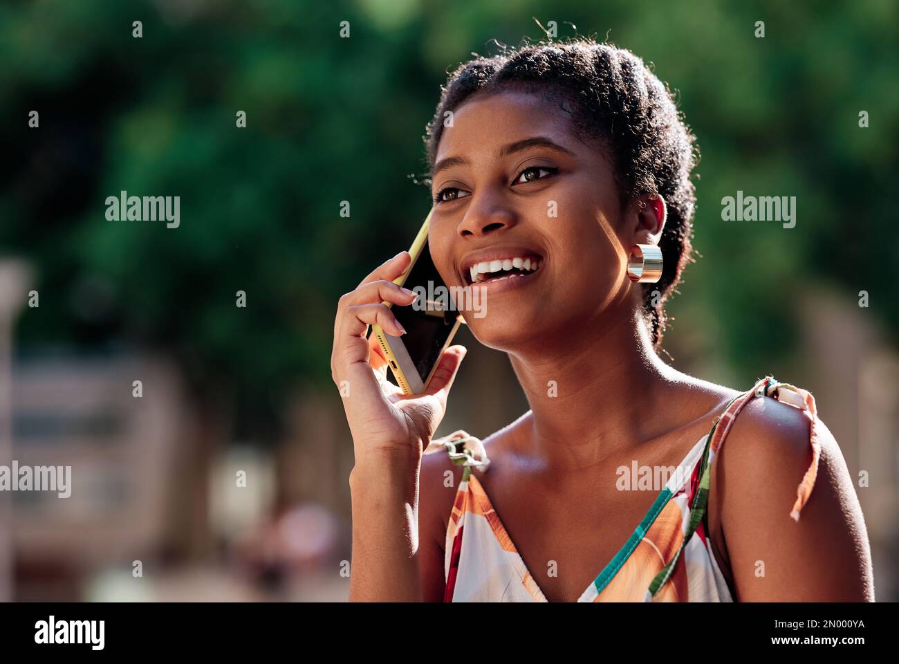 Young woman smiling while talking on the phone outdoors Stock Photo - Alamy