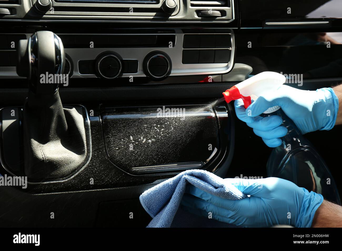 Man in gloves cleaning car dashboard with disinfectant spray and rag ...