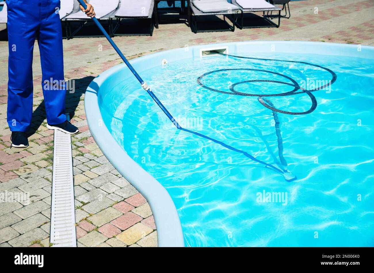 Worker cleaning outdoor swimming pool with underwater vacuum, closeup ...
