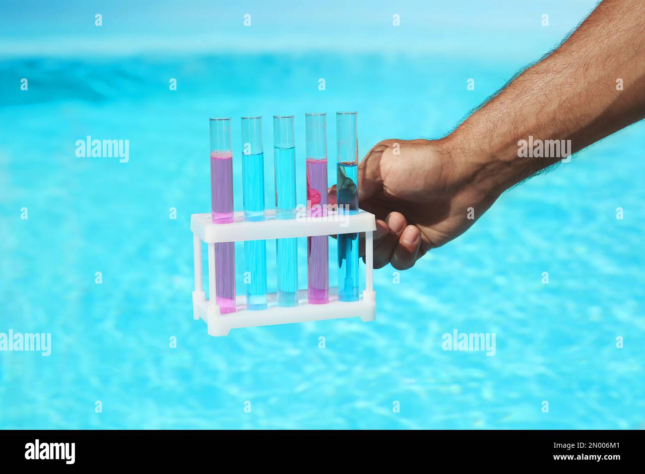 Man holding test tubes with reagents near swimming pool, closeup Stock ...