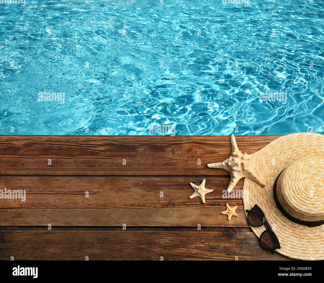 Beach accessories on wooden deck near swimming pool, flat lay. Space ...