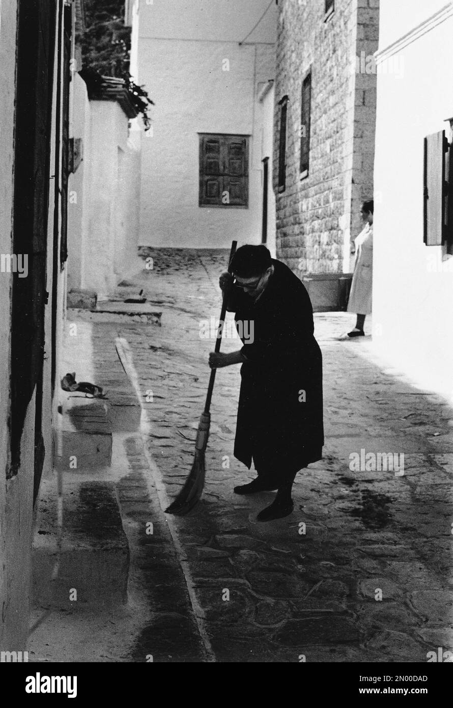 An elderly woman sweeps her part of the whitewashed streets on the ...