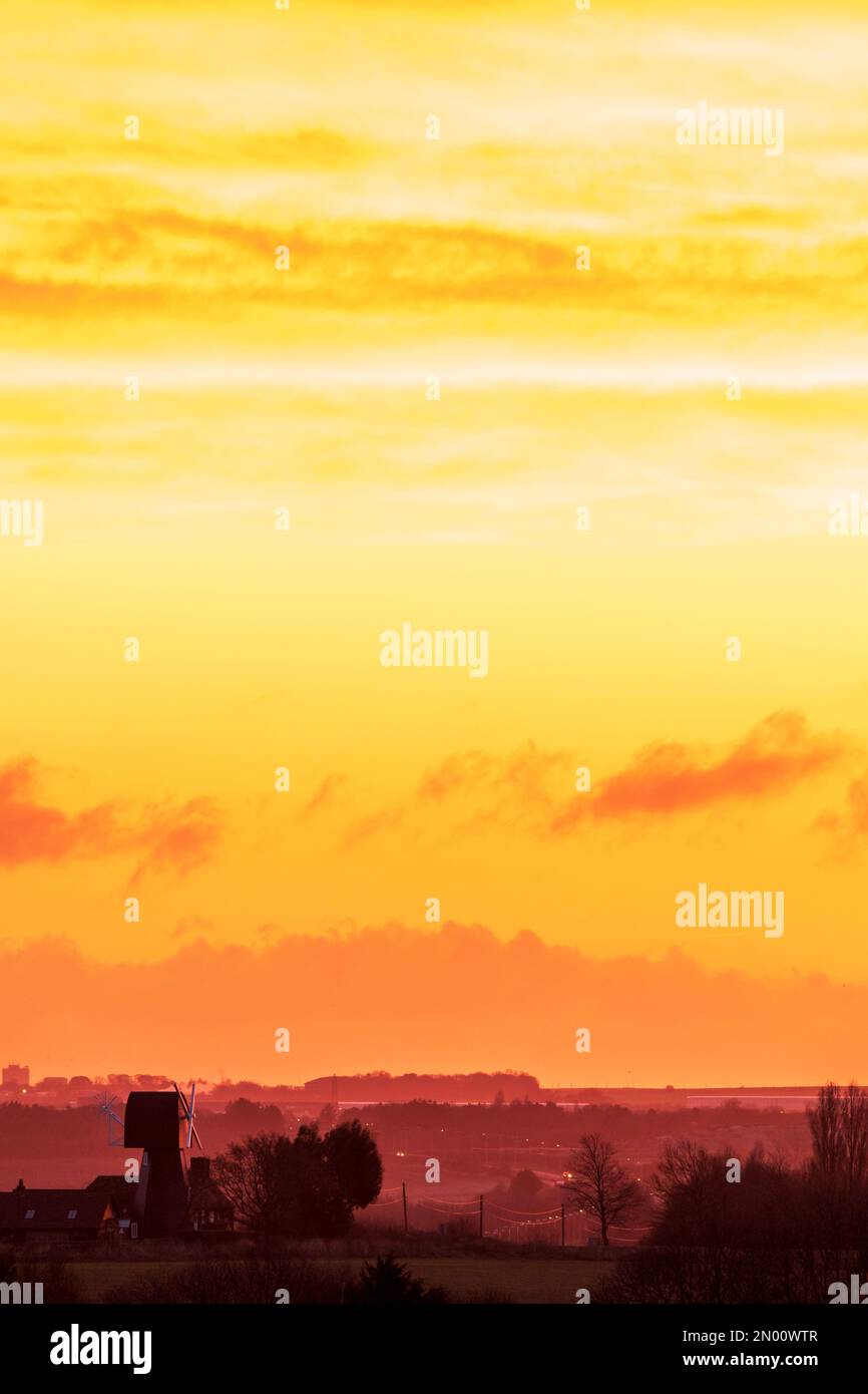 A beautiful dawn sky of yellow and orange clouds over the landscape at ...