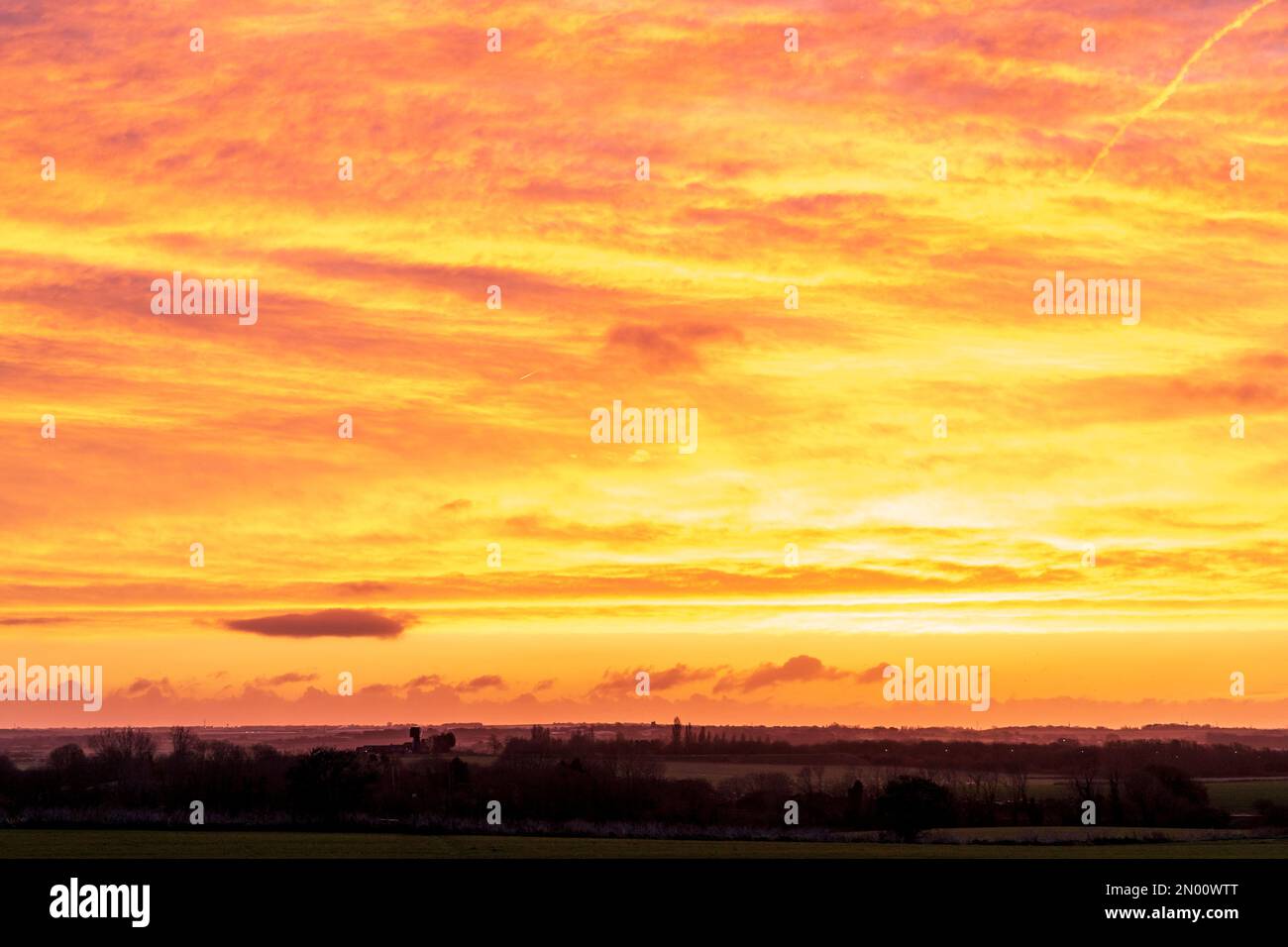 A beautiful dawn sky of yellow and orange clouds over the landscape at ...