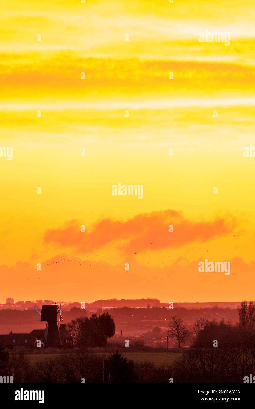 A beautiful dawn sky of yellow and orange clouds over the landscape at ...