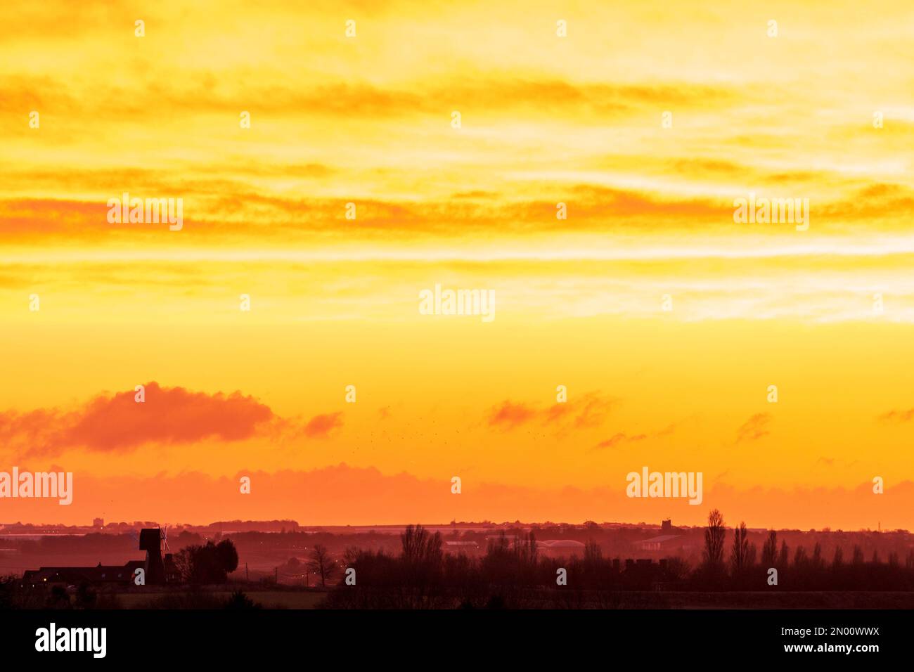 A beautiful dawn sky of yellow and orange clouds over the landscape at ...