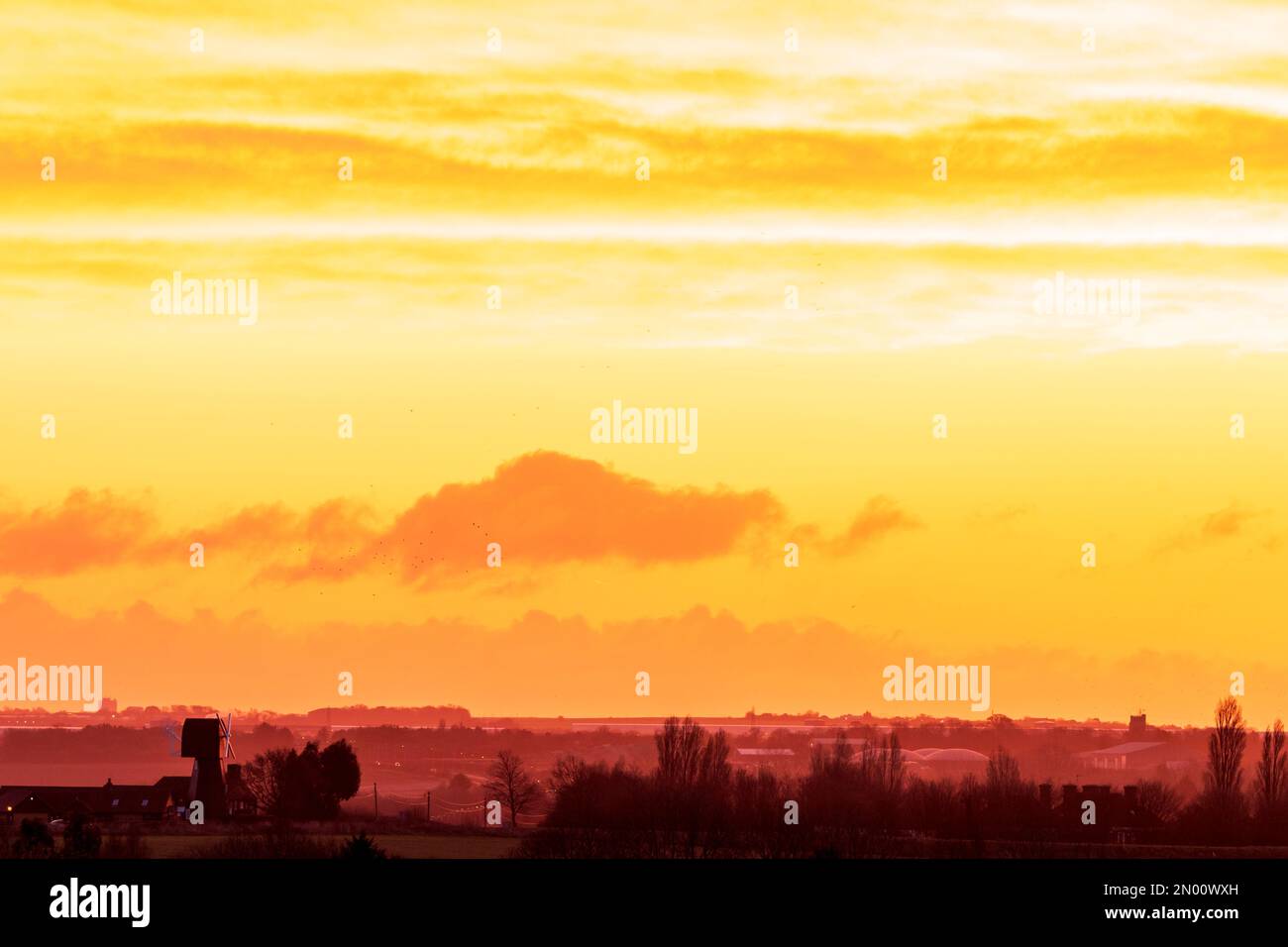 A beautiful dawn sky of yellow and orange clouds over the landscape at ...