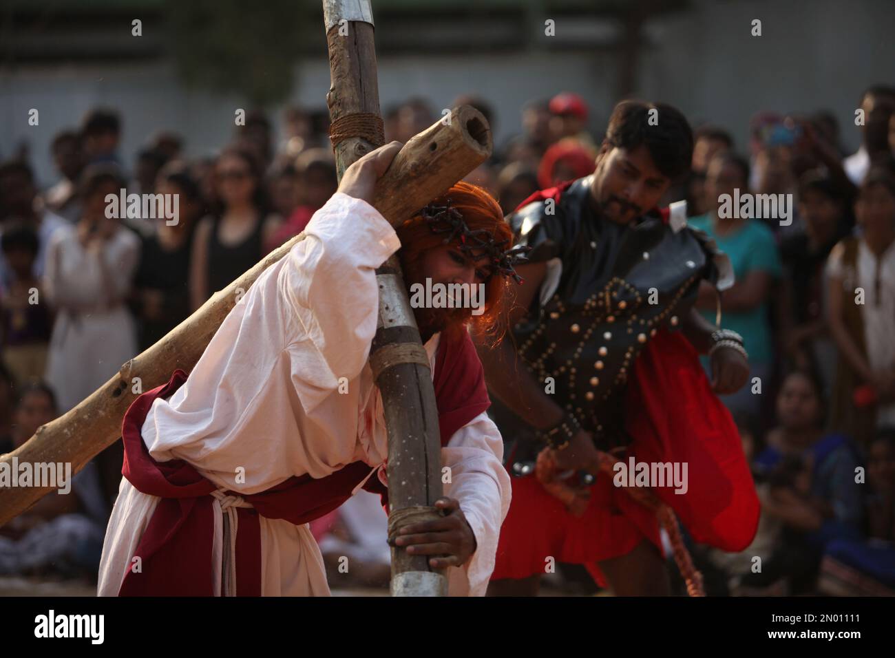 An unidentified Indian actor dressed as Jesus Christ carries a cross as ...