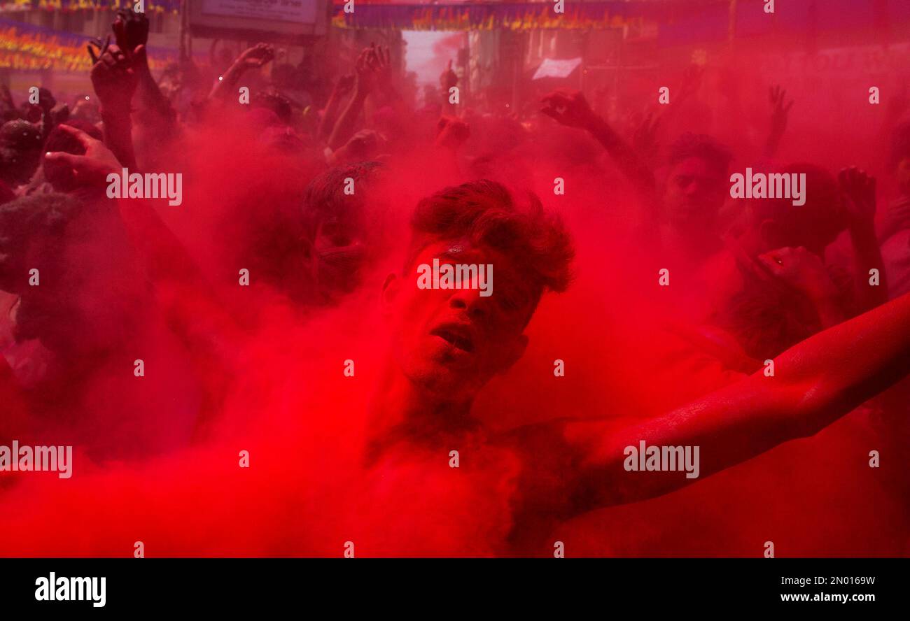 Indian revelers, faces smeared with colored powder, dance during ...
