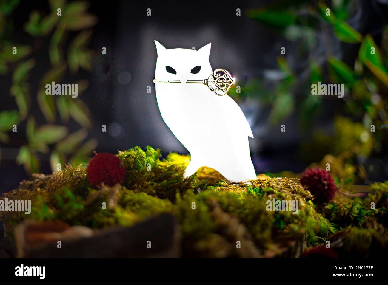 Glowing white owl with a key in its beak, magical still life set in the ...