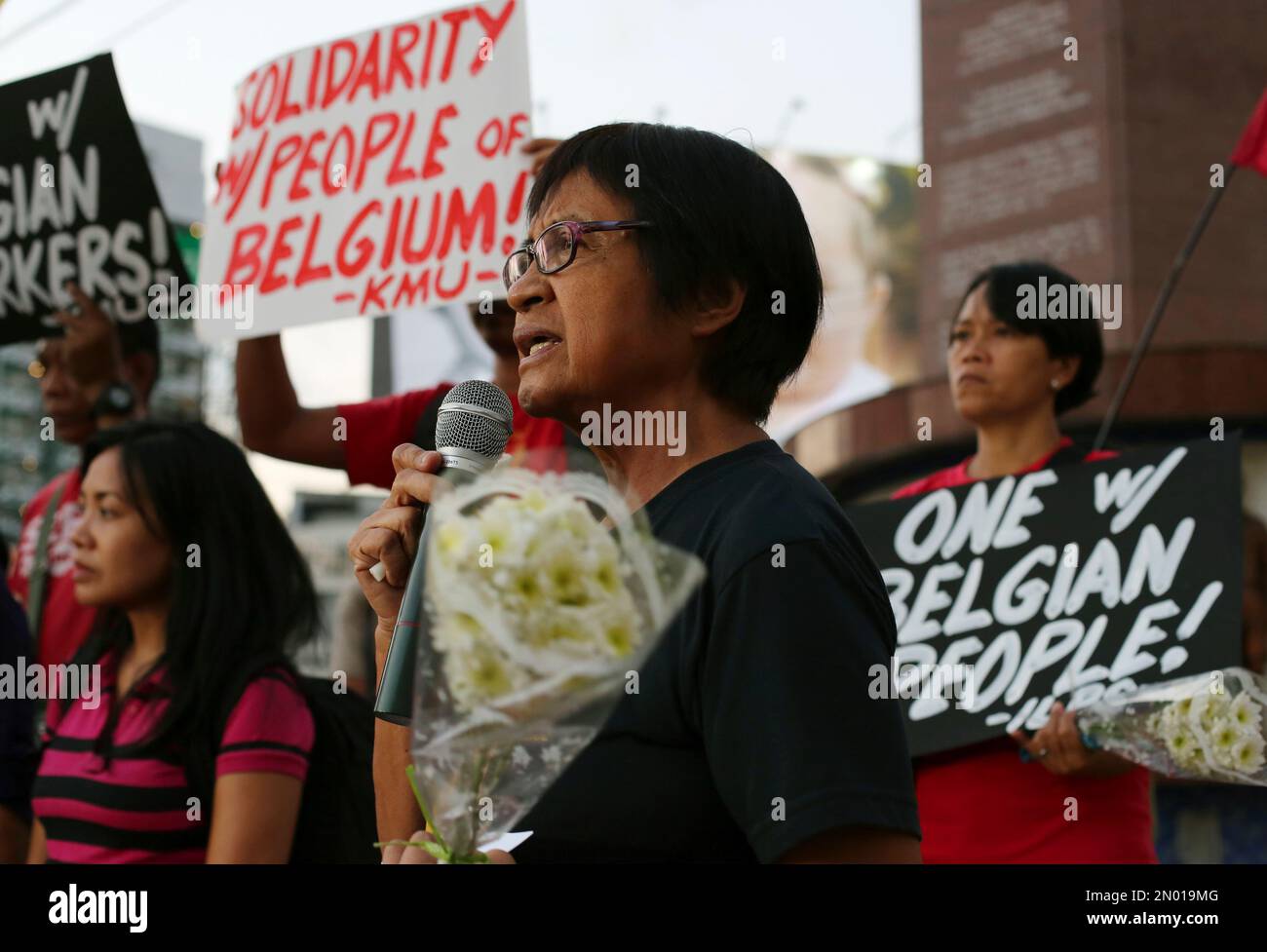 A Filipino activist holds a bouquet of flowers as she speaks during a ...