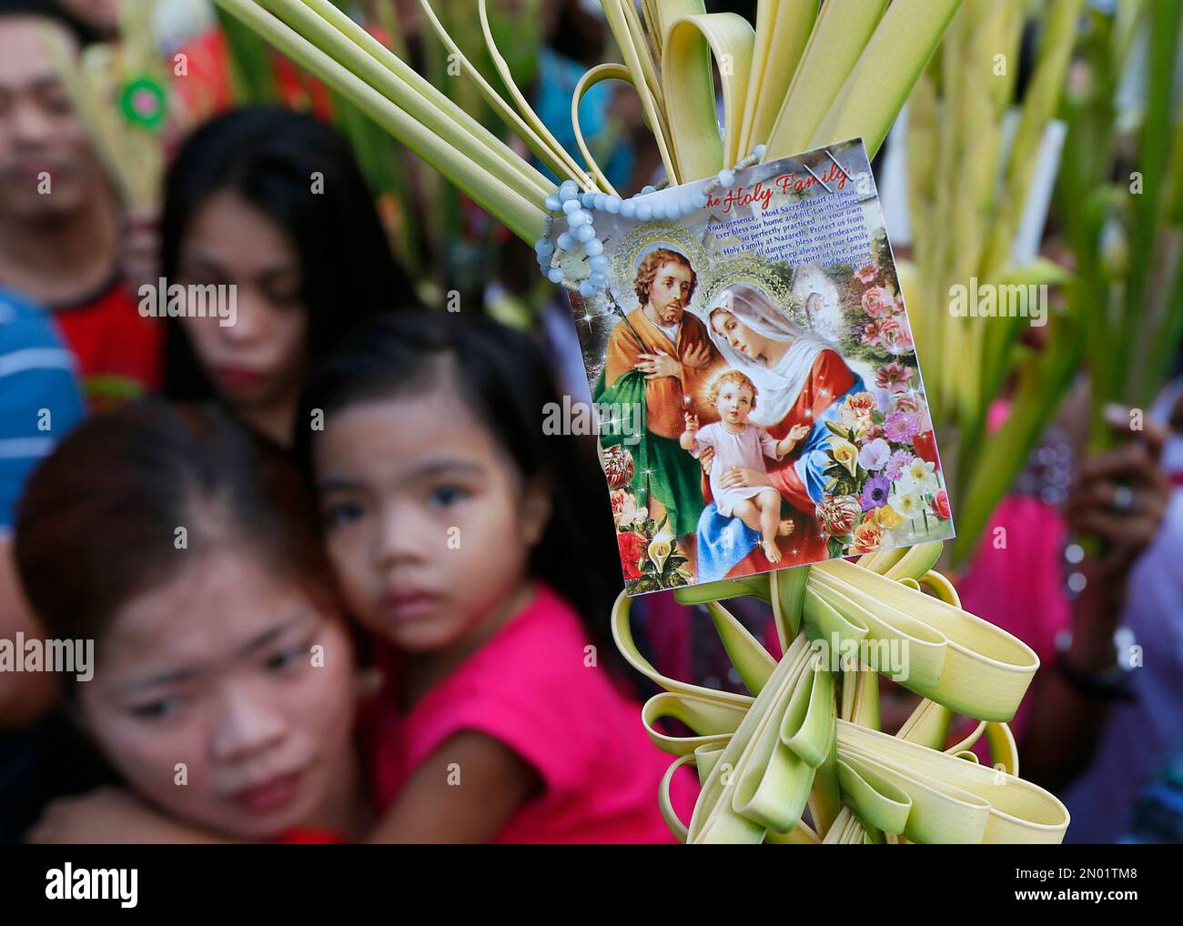 Roman Catholic devotees carry palm fronds to be blessed by a priest as ...