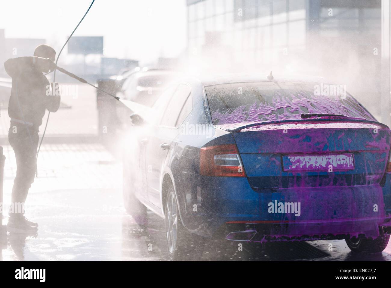 Process of man washing his car in a self-service car wash station. Back ...
