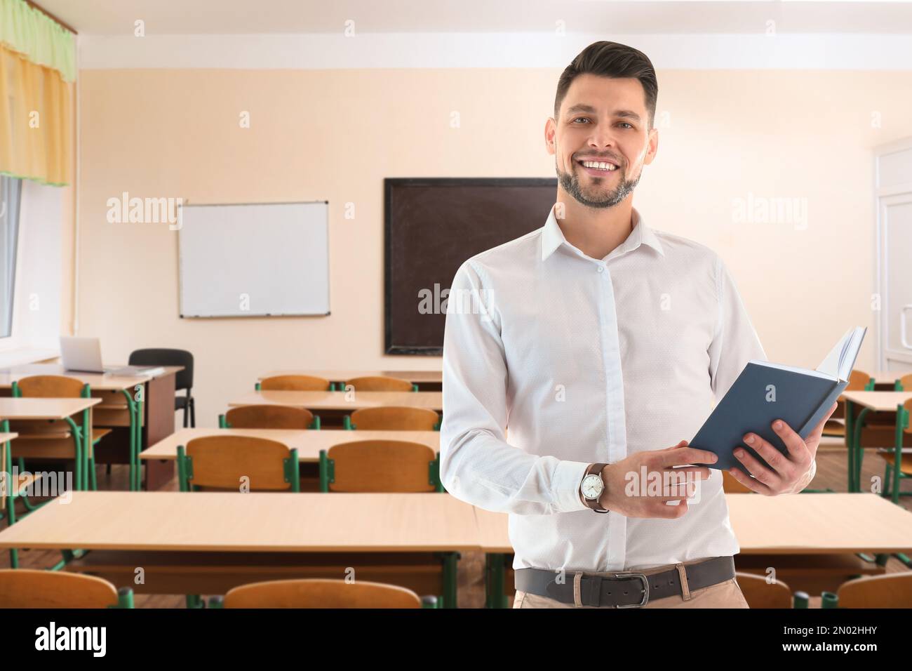 Teacher with book waiting for students in classroom Stock Photo - Alamy