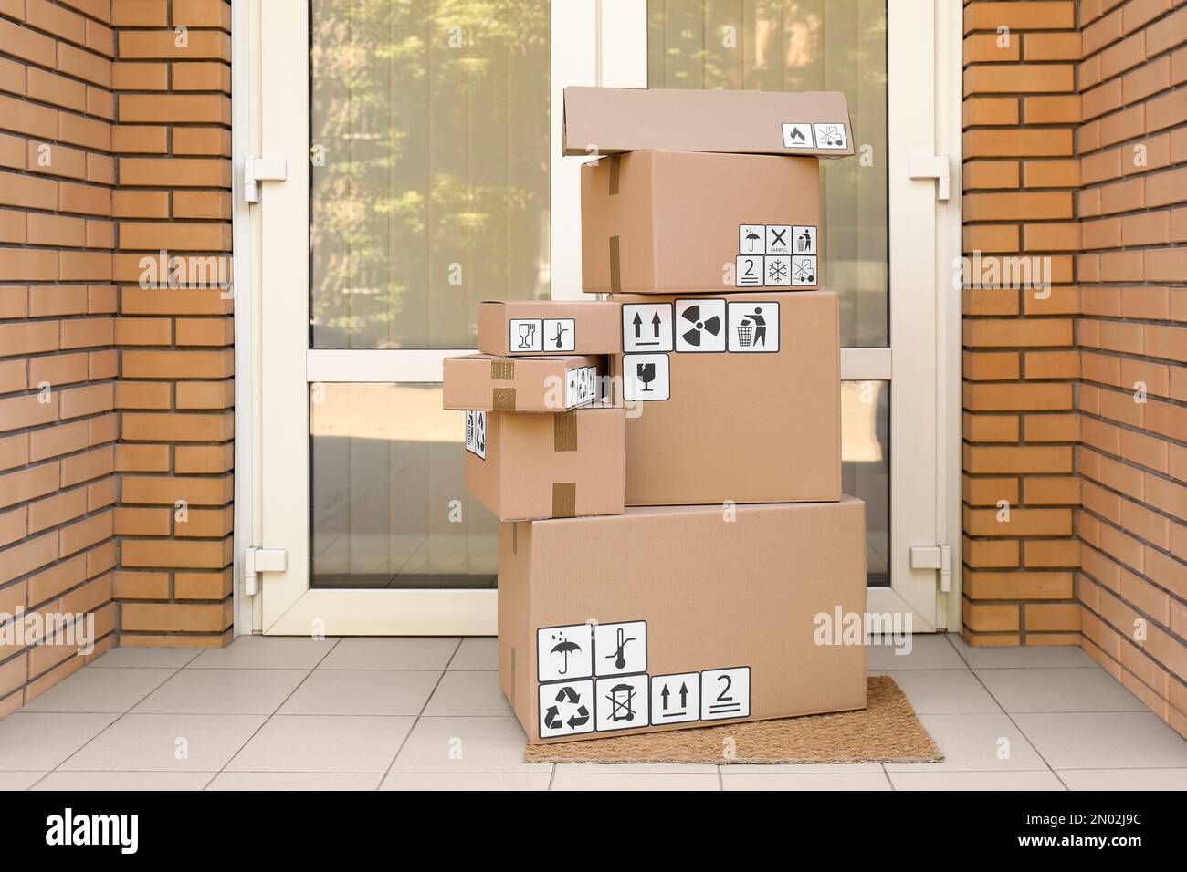 Cardboard boxes with different packaging symbols on door mat near ...