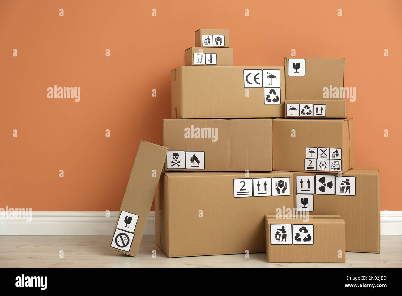 Cardboard boxes with different packaging symbols on floor near orange ...